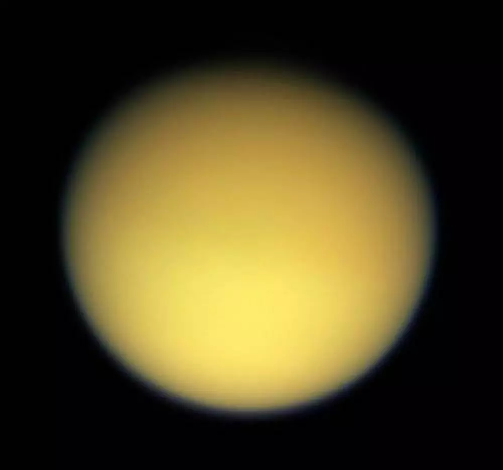 Titan în culori naturale. Diametrul satelitului este de aproximativ 5,1 mii km, adică aproximativ 0,4 din cel al pământului, iar temperatura medie a suprafeței este de -180 Celsius