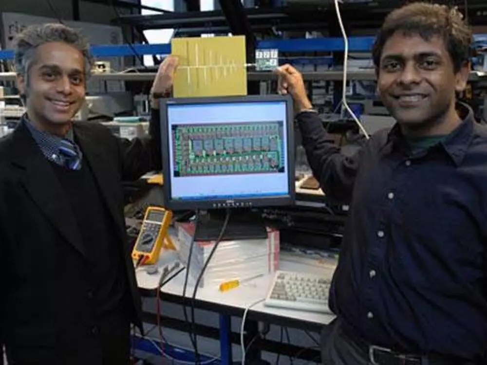 Le professeur Rahul Sarpeshkar et Soyumajit Mandal montrent leur exploit : l'étudiant tient la puce elle-même et le professeur tient l'antenne. Le dispositif du microcircuit est affiché sur le moniteur