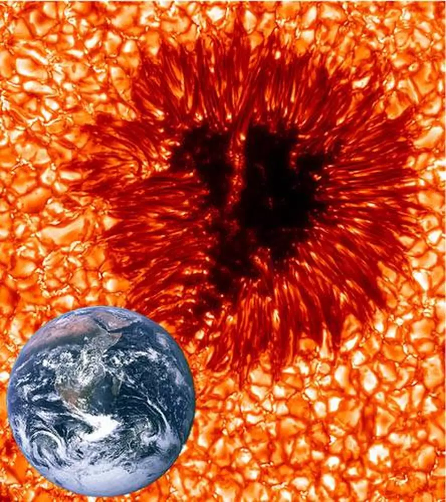 Aurinkoteleskoopilla otettu kuva auringonpilkusta. Maa näkyy mittakaavassa