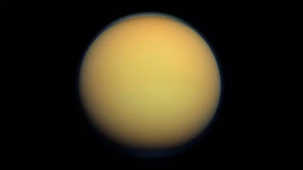 En la imagen de la sonda Cassini, Titán está rodeado por una neblina azulada de una atmósfera densa.