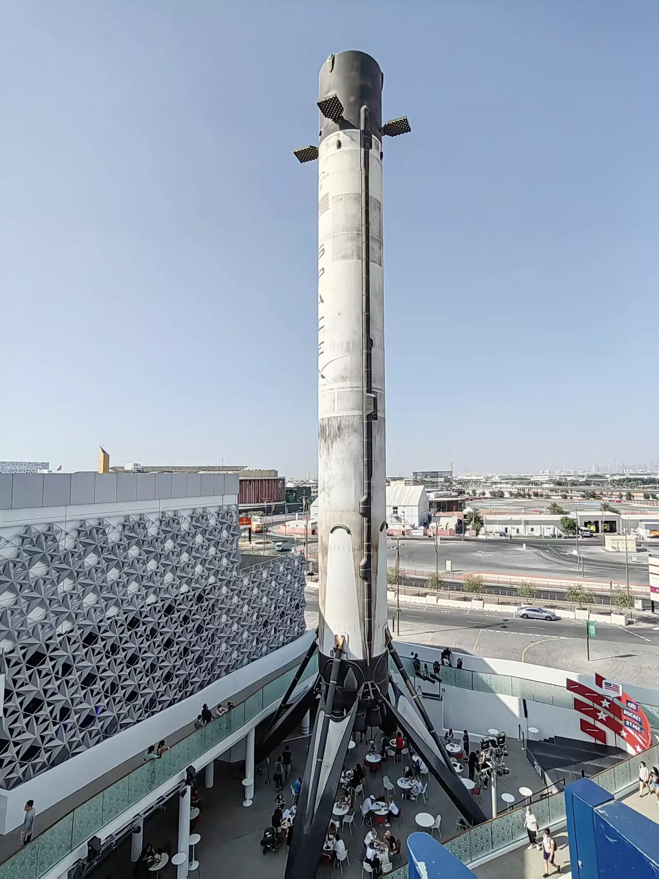 Show stoper amerického pavilonu je návratovým stupněm SpaceX. Lidé mimochodem zejména nesbírají. Ledaže by turisté nejedli hamburgery pod začištěnými tryskami motoru.